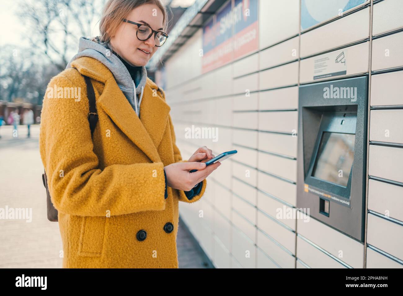 Self service post terminal machine and parcel sending. Woman holding ...