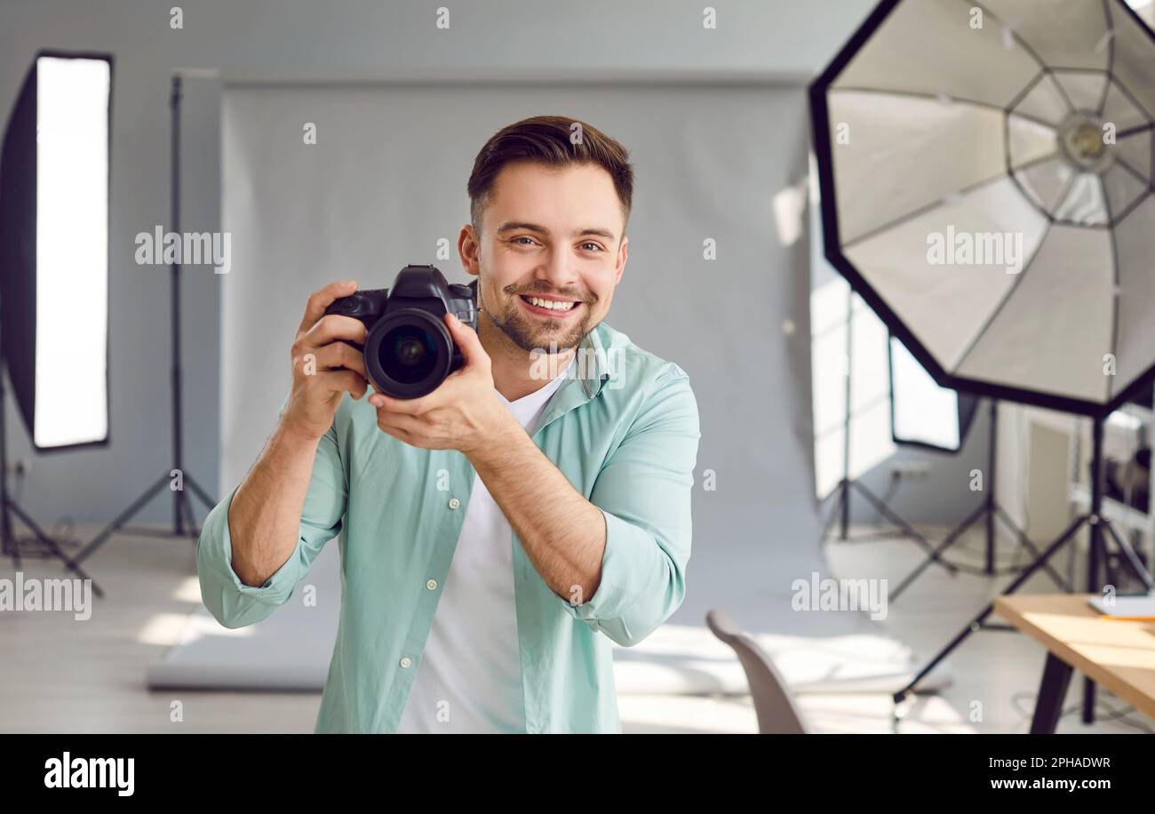 Happy smiling photographer holding a camera standing in professionally ...