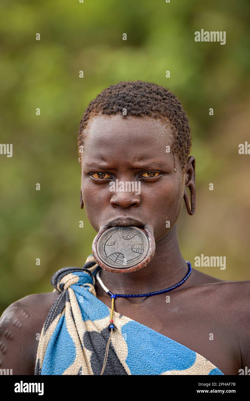 A portrait of a young Mursi woman with a large lip plate, a traditional ...