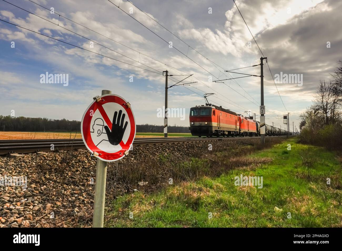 caution sign at a crossing with an approaching fast train with clouds ...