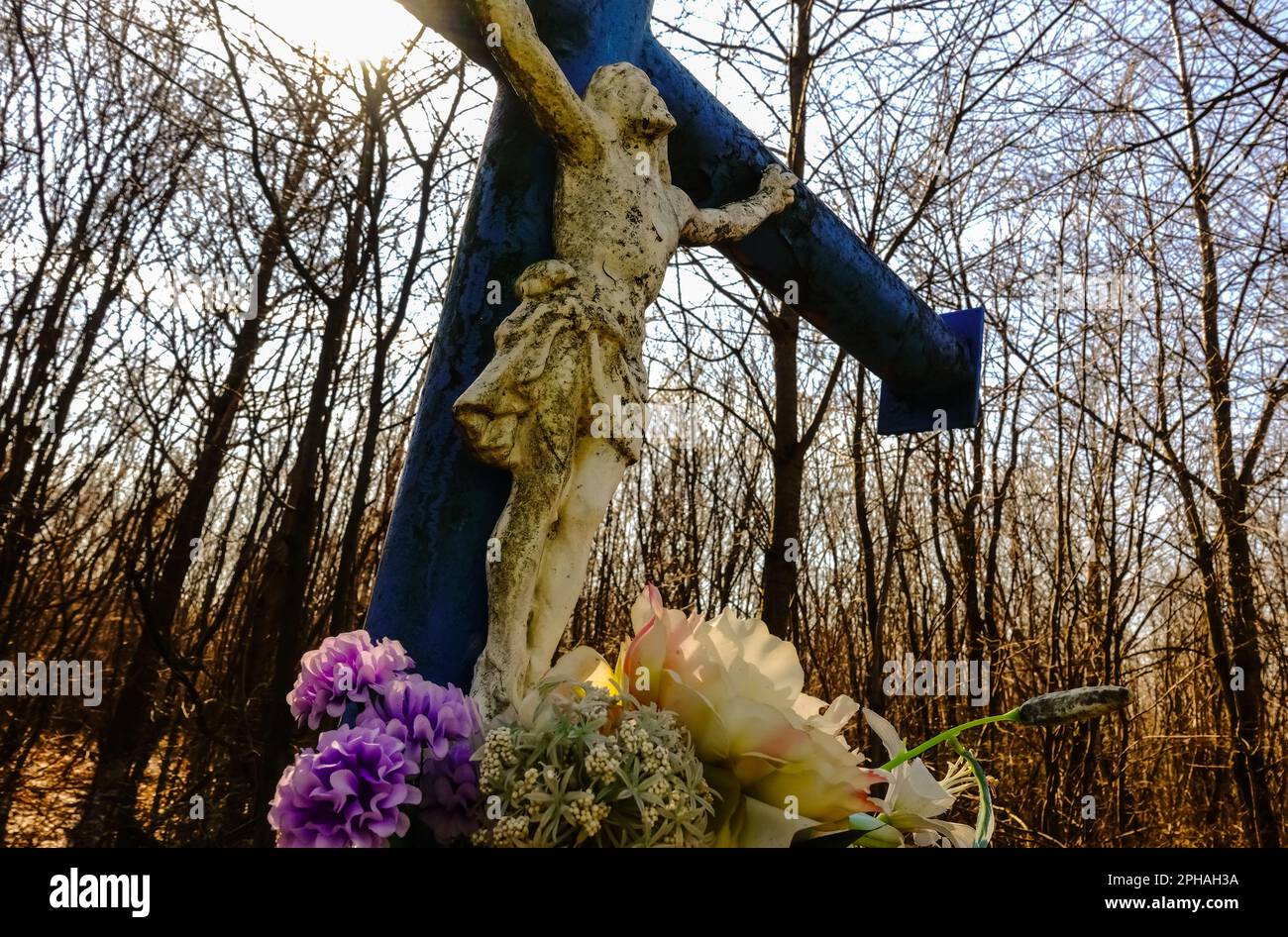 cross with jesus and fresh flowers on a mountain with forest during ...