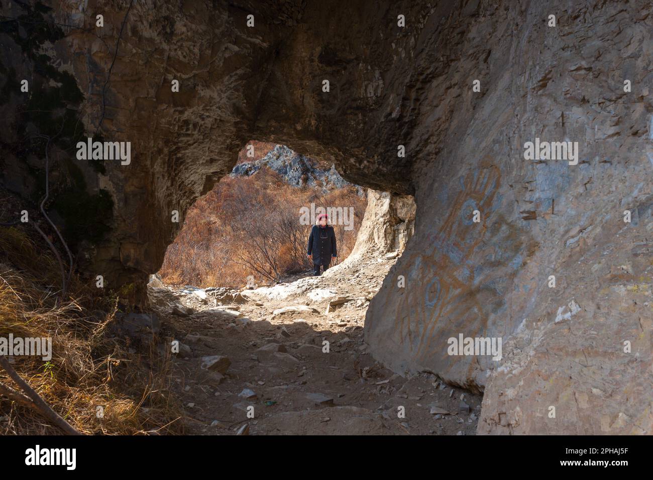 The exit from the cave with an elderly woman hiker among the stones ...