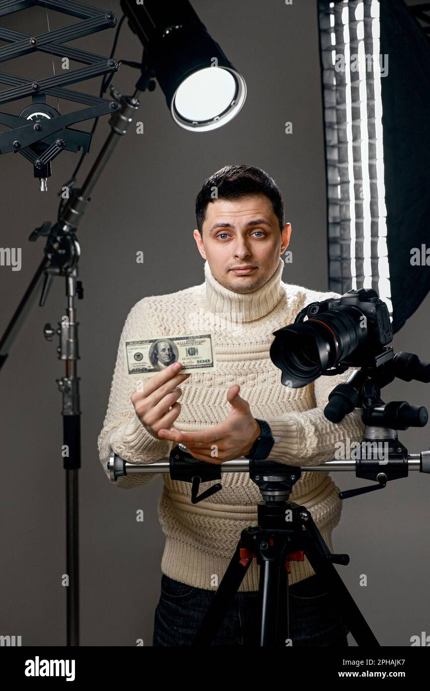 photographer with digital camera on tripod holding hundred dollar bills ...