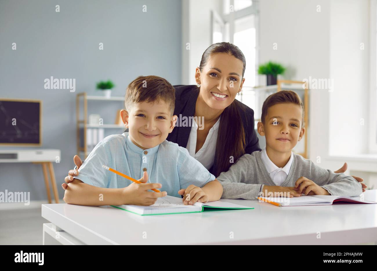 Portrait of friendly female teacher with two happy schoolchildren ...