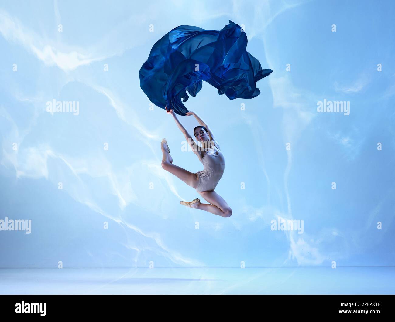 Shot of flexible ballerina, dancer in high jump with navy fabric over ...