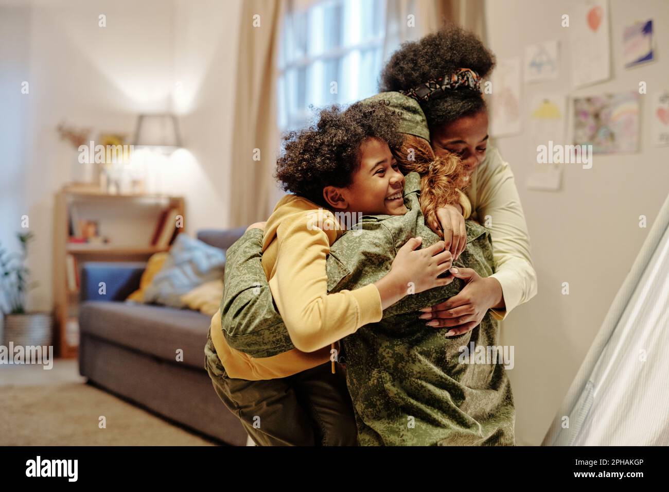 Happy boy and his mother giving hug to young man in camouflage uniform ...
