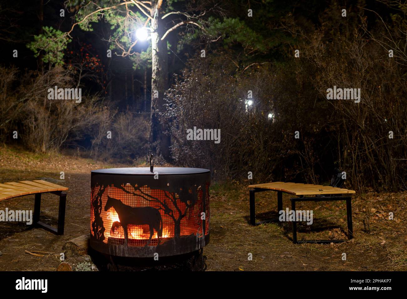 A fire bowl, a metal hearth, with a silhouette of a horse, surrounded ...