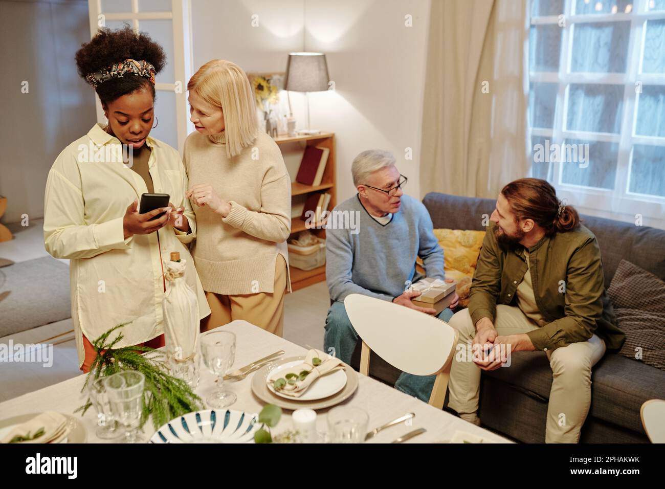 Two intercultural women discussing photos in smartphone held by one of ...