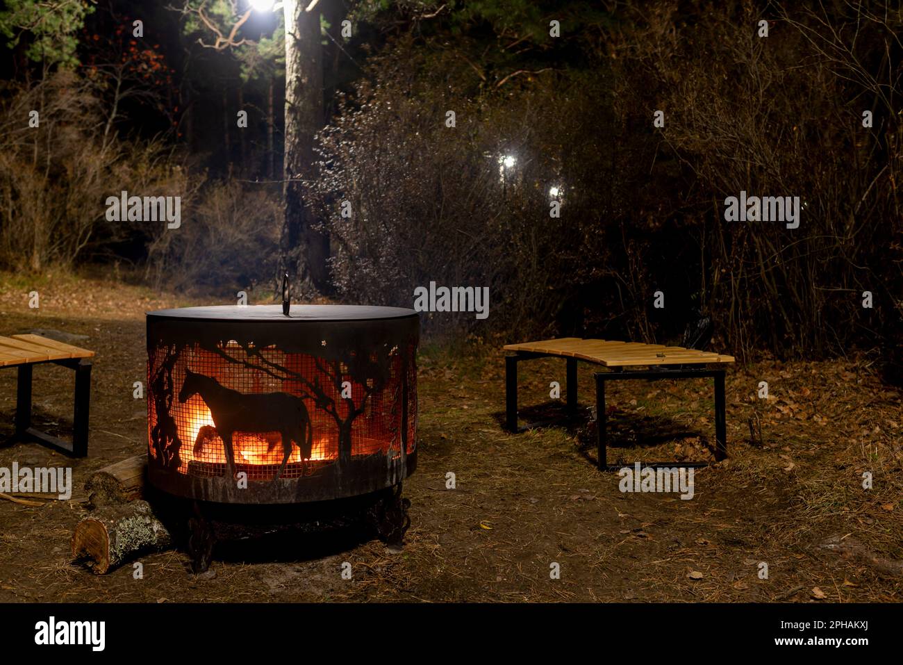 A fire bowl, a metal hearth, with a silhouette of a horse, surrounded ...
