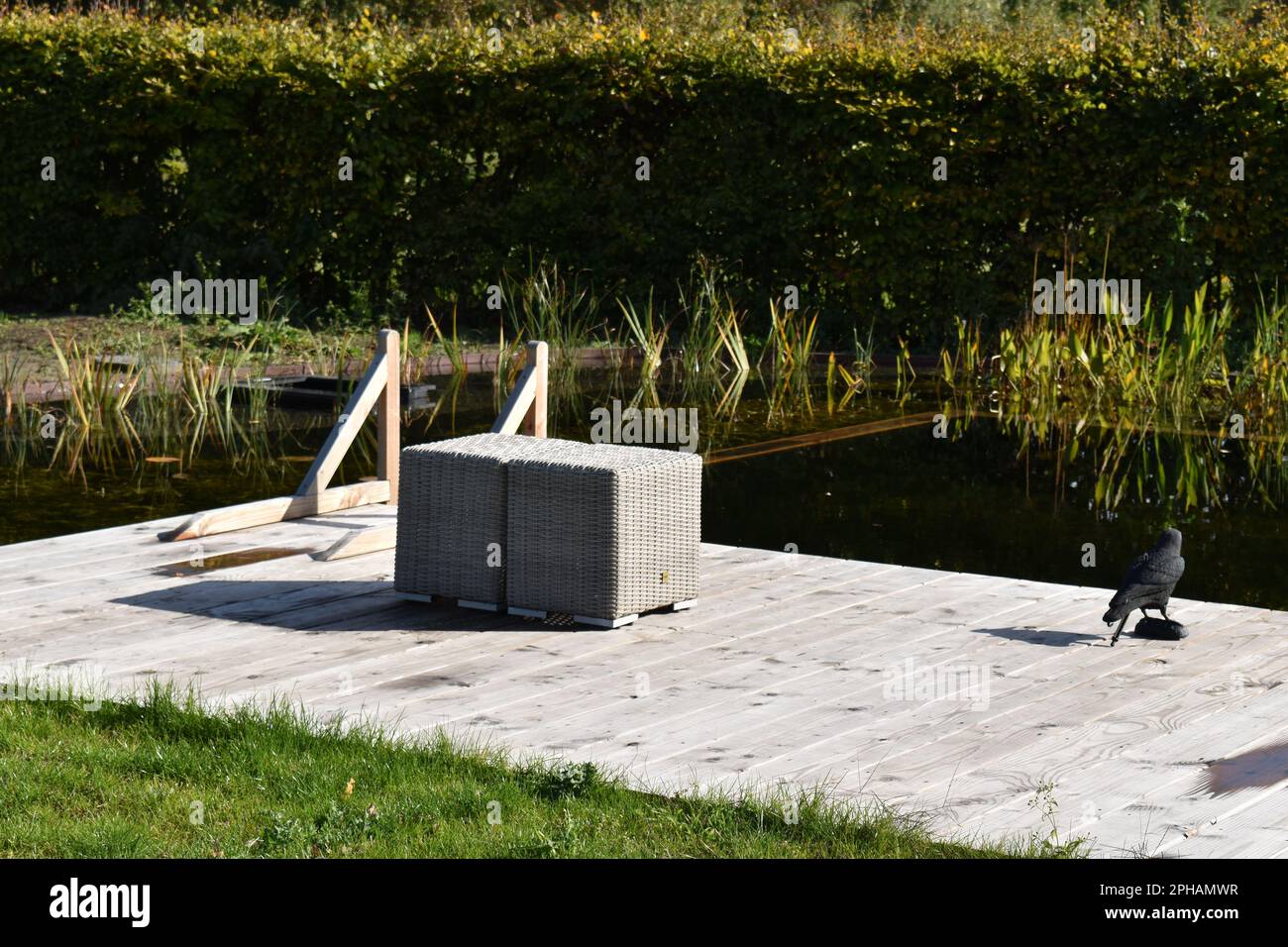 A swimming pond with a wooden decking, a wooden stairs, a plastic stool ...