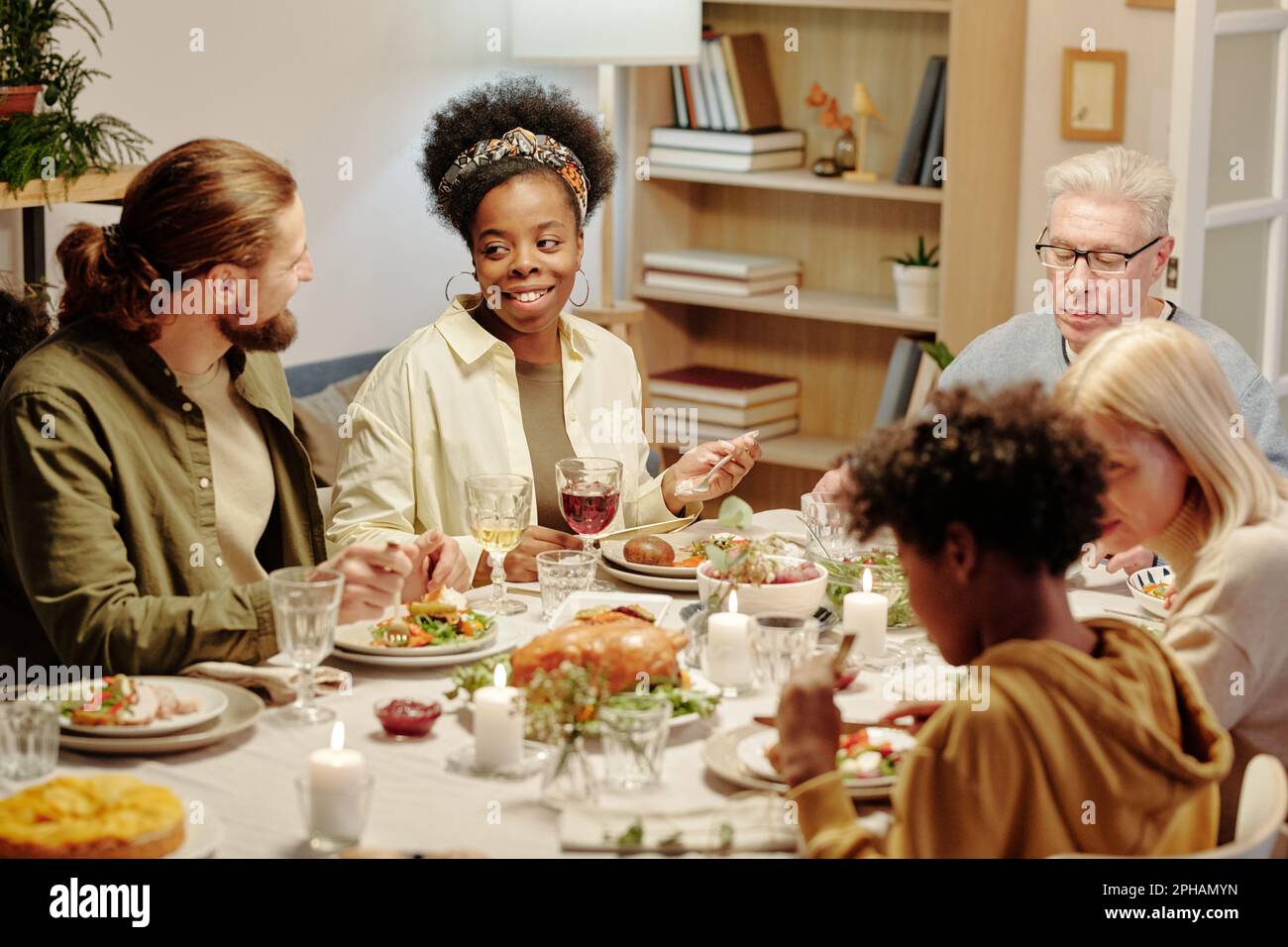Happy young intercultural couple chatting by served table while ...