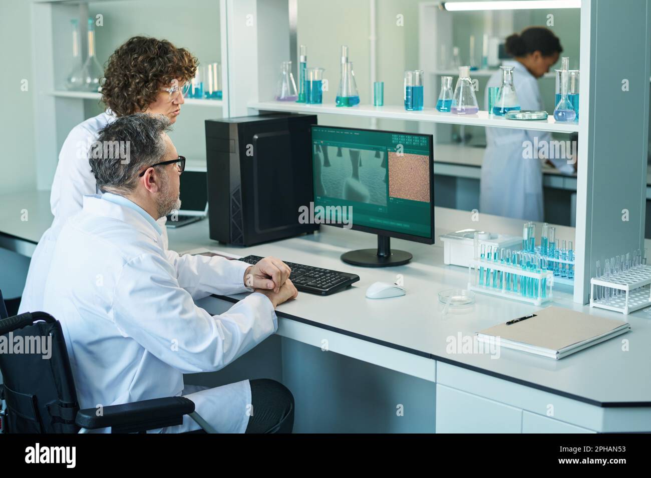 Side view of two professional virologists in lab coats discussing virus ...