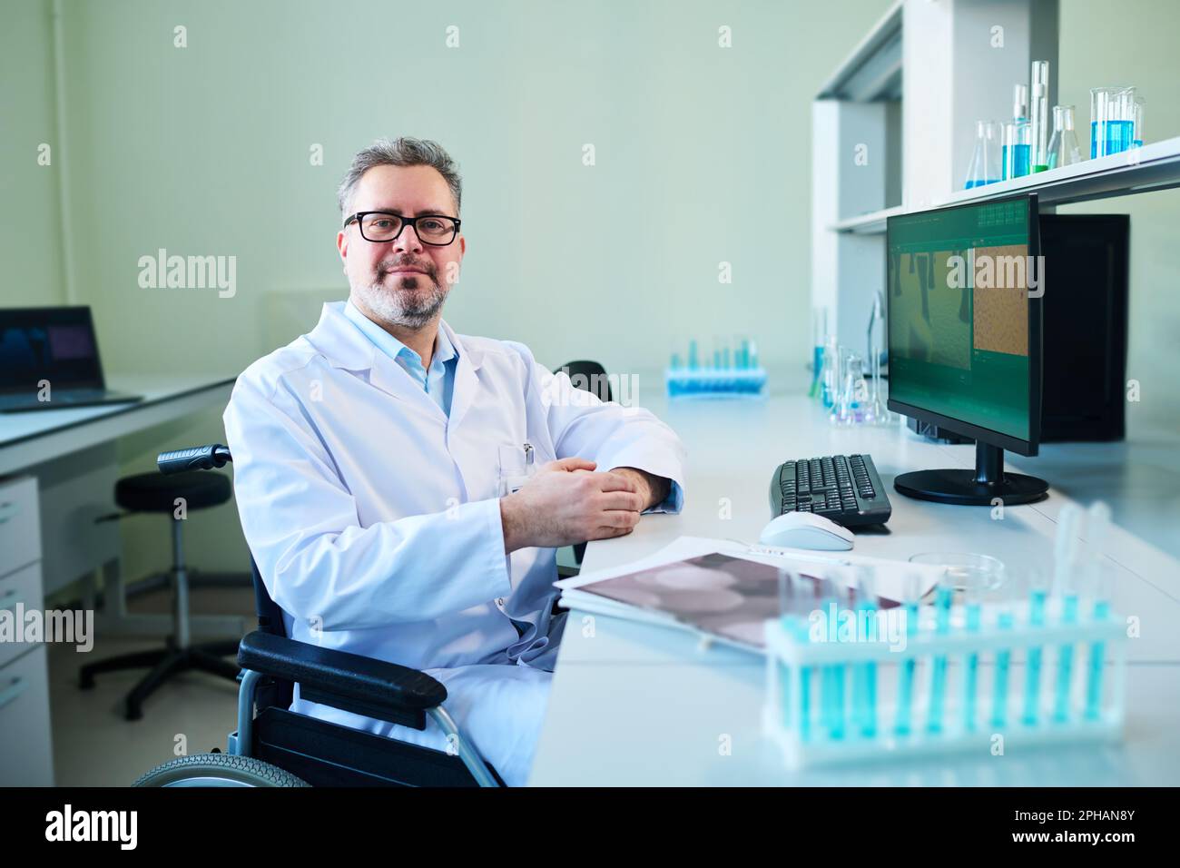 Successful mature male virologist in lab coat and eyeglasses sitting in ...