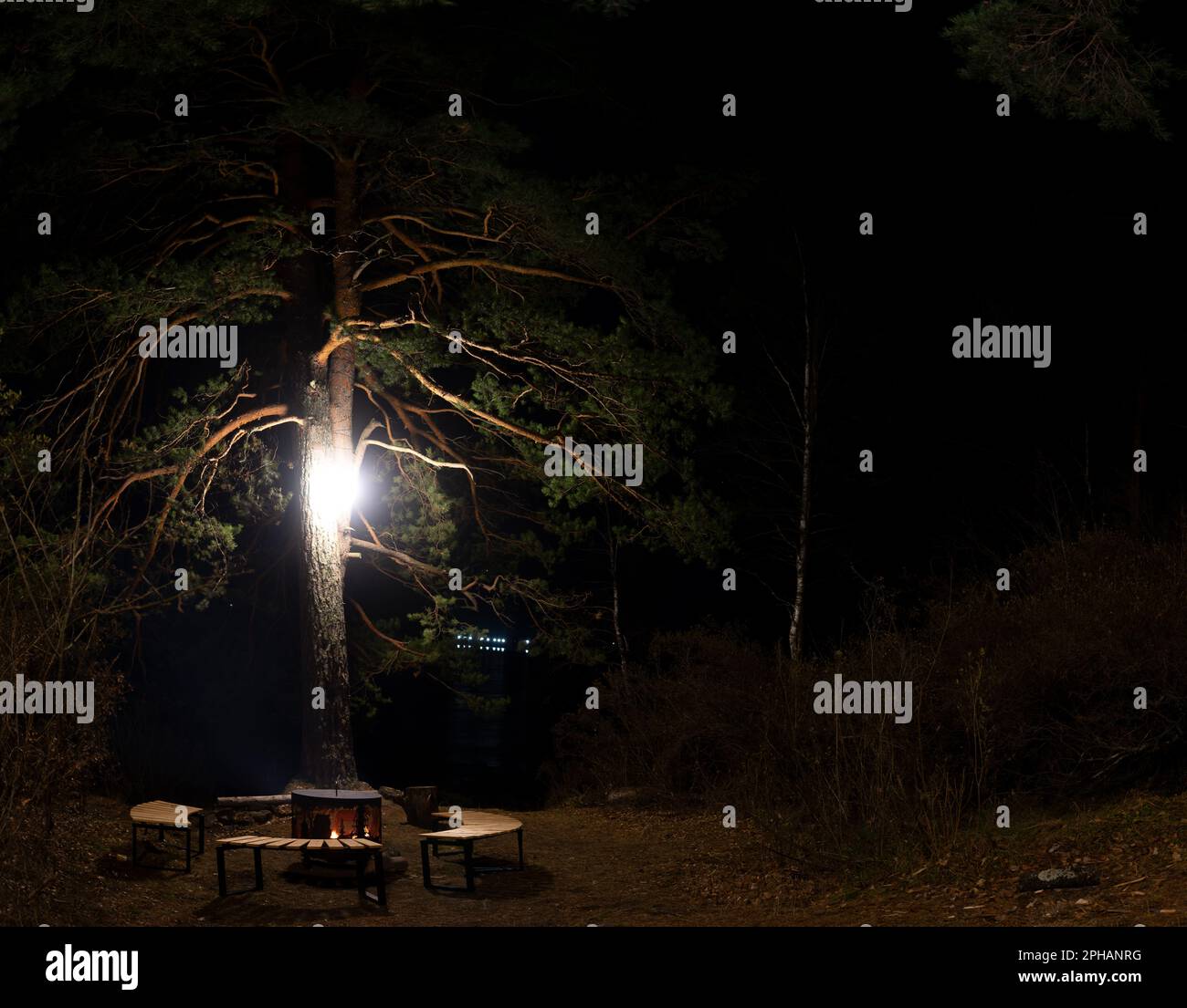 A fire bowl, a metal hearth surrounded by wooden benches, stands at ...
