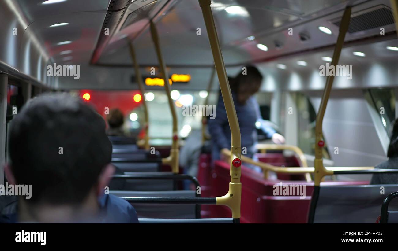 Back of bus with people commuting from work at night. Person exiting ...