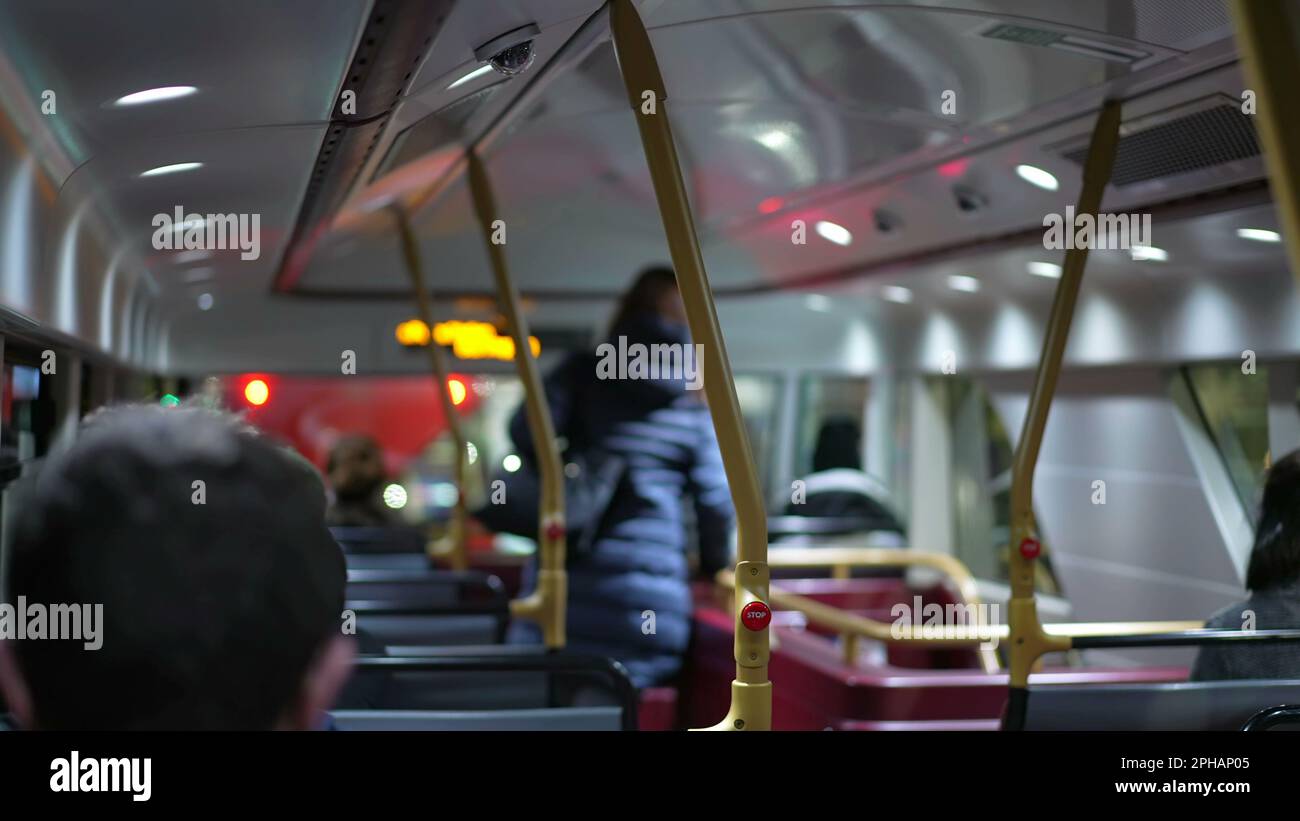 Back of bus with people commuting from work at night. Person exiting ...