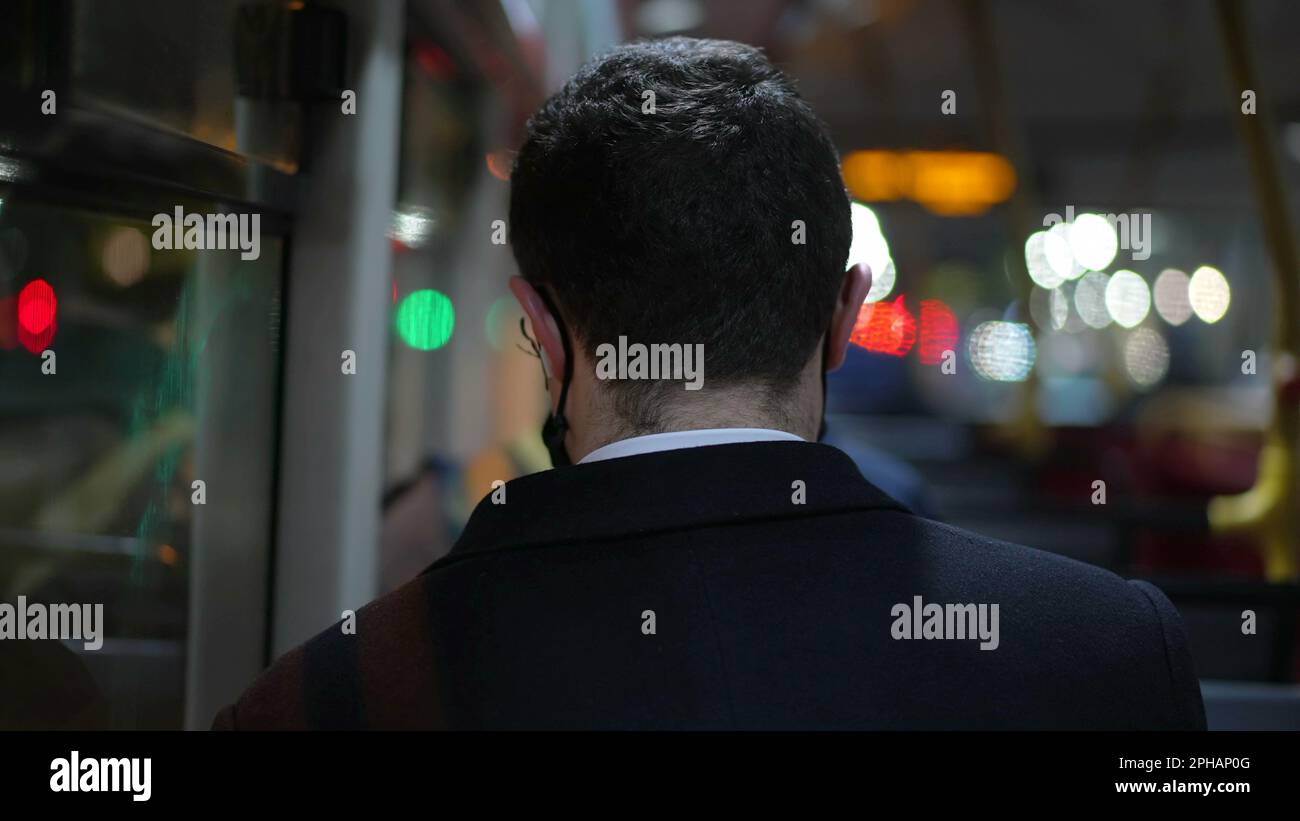 Back of male commuter riding bus at night after work. Passenger sitting ...