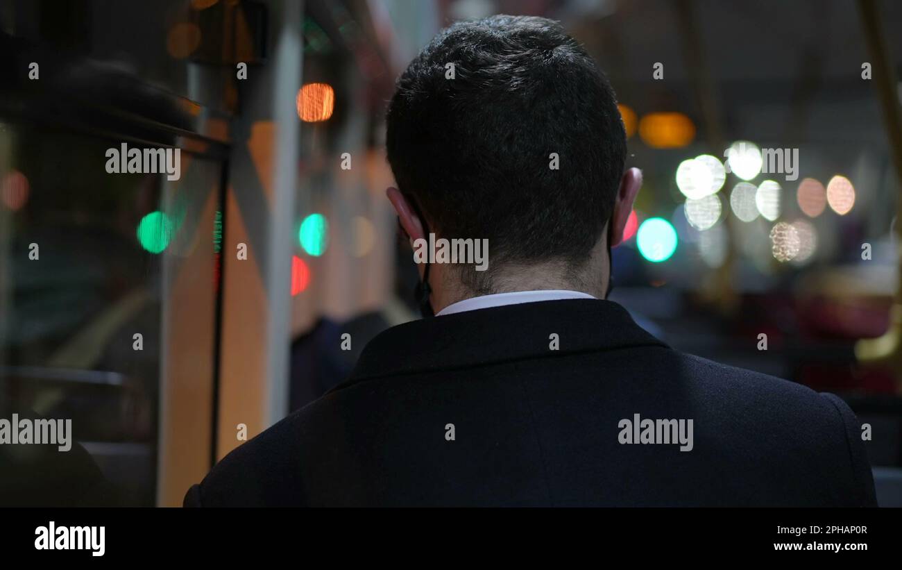 Back of male commuter riding bus at night after work. Passenger sitting ...
