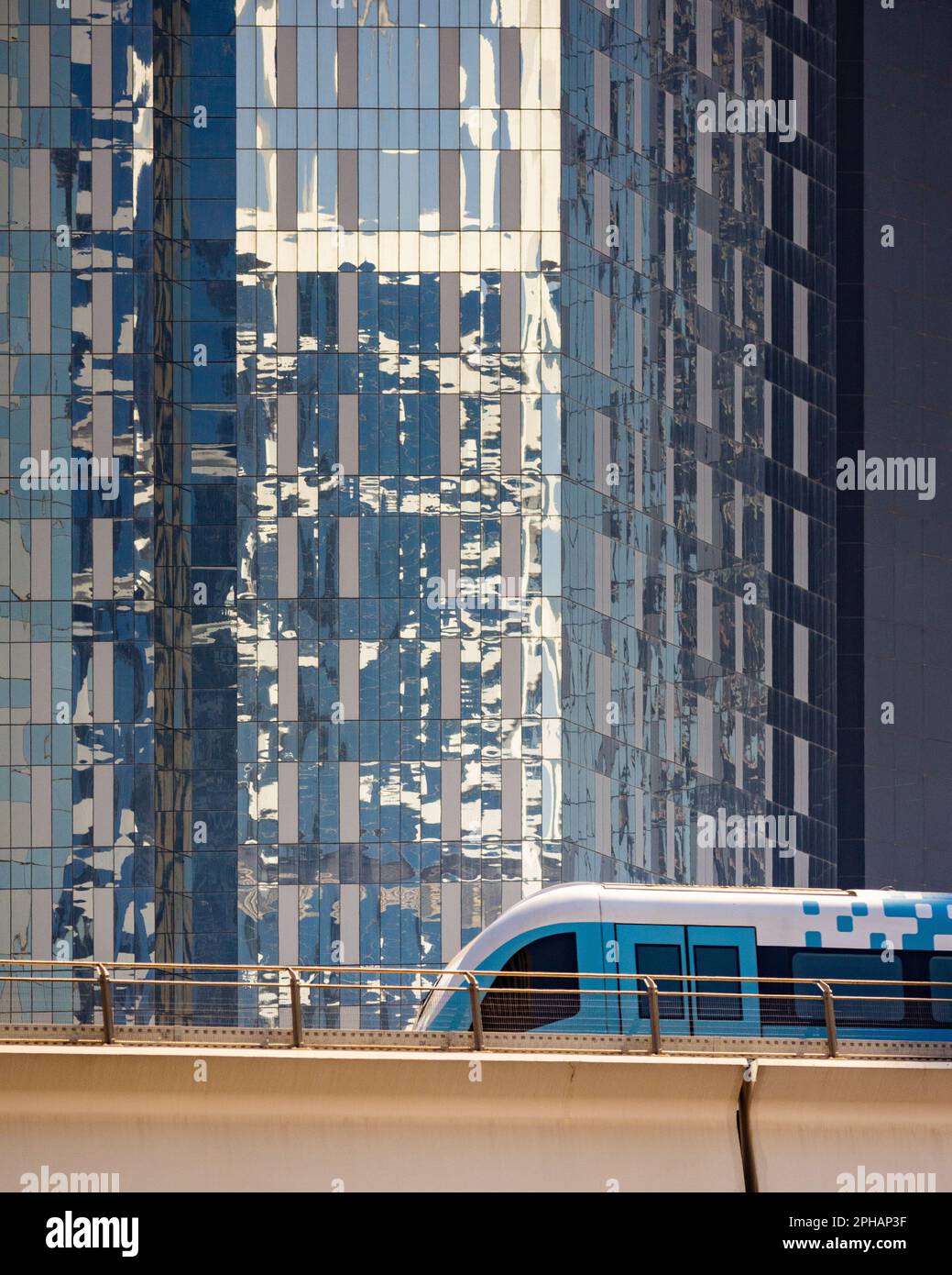 A modern train moves through an urban cityscape with mirrored glass-and ...