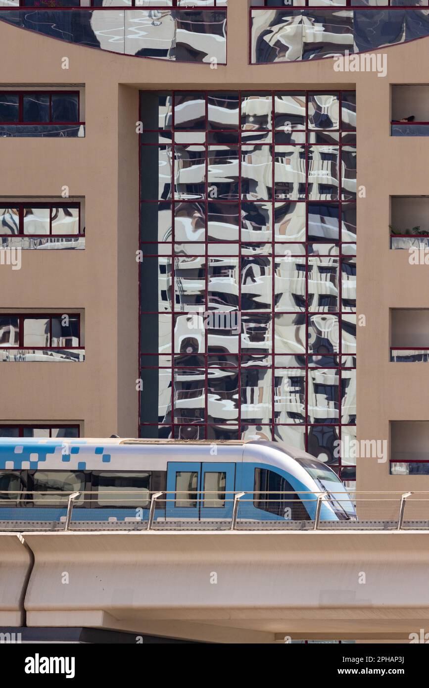 A modern train moves through an urban cityscape with mirrored glass-and ...
