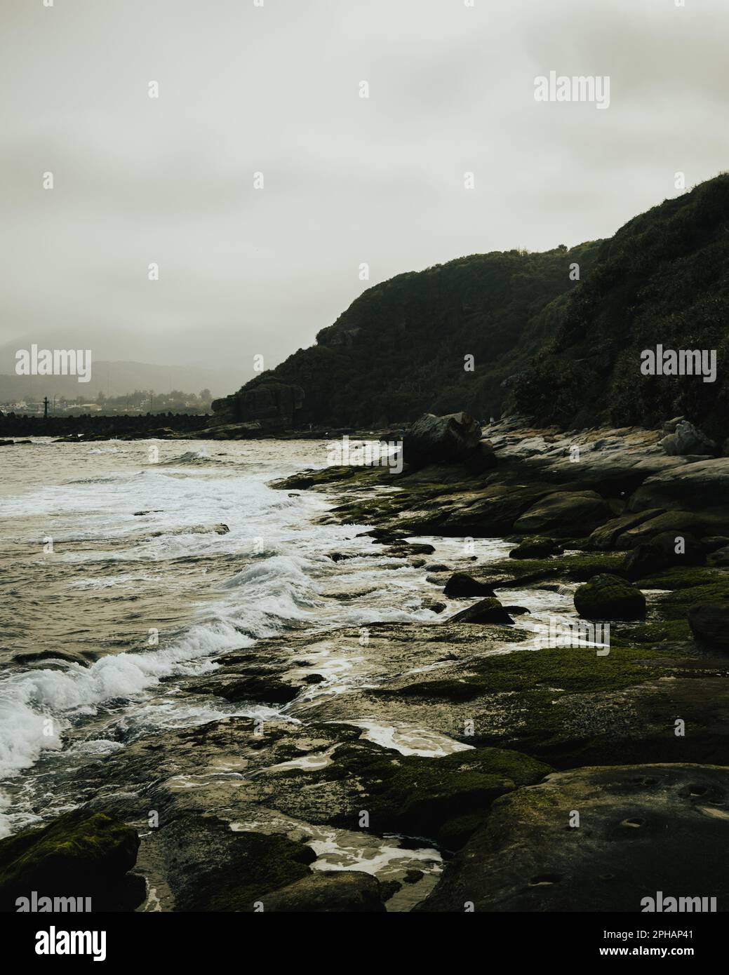 A picturesque ocean shore featuring a rocky beach with waves lapping ...