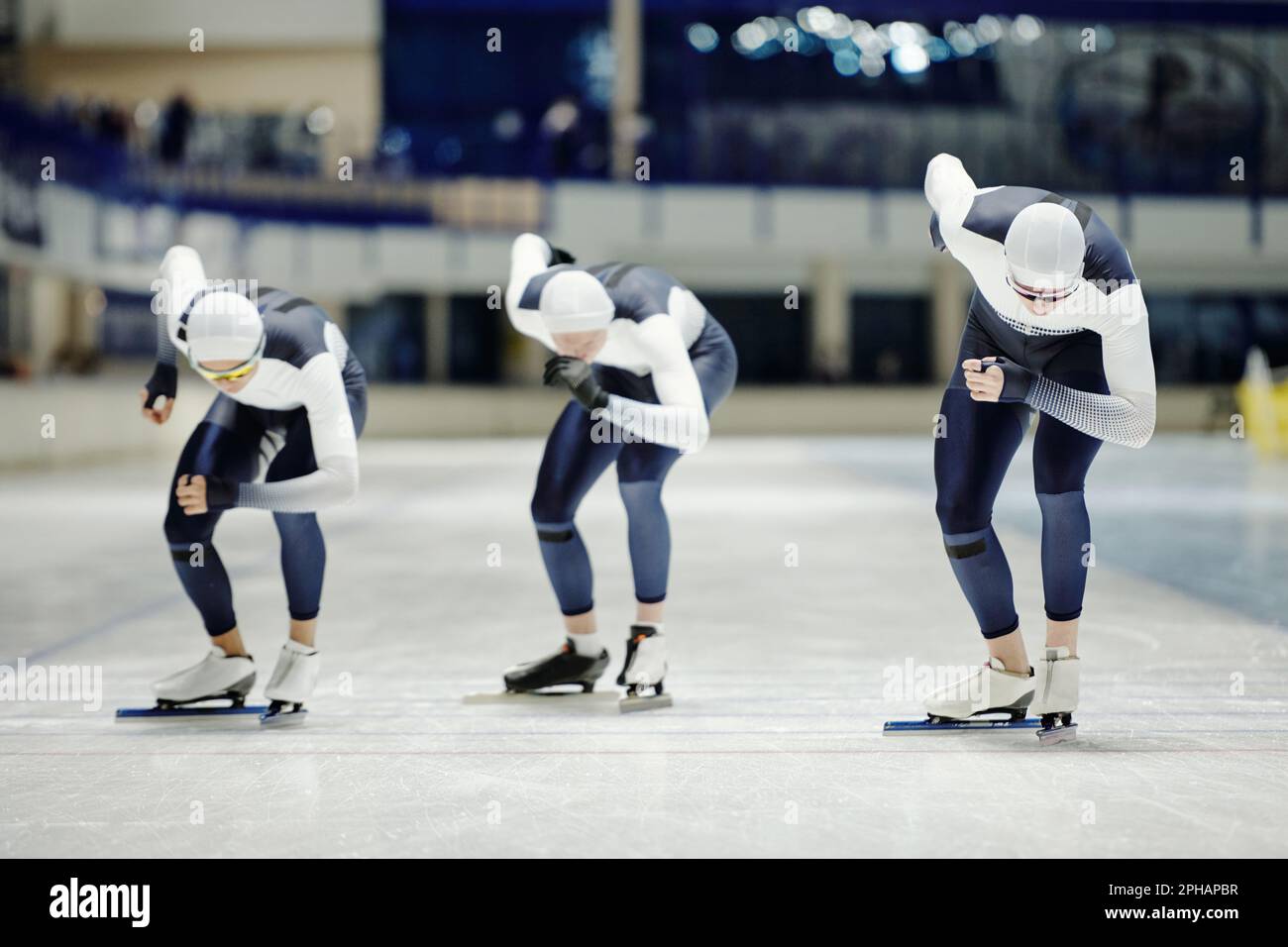 Three young male ice skaters in sports uniform and skates sliding along ...