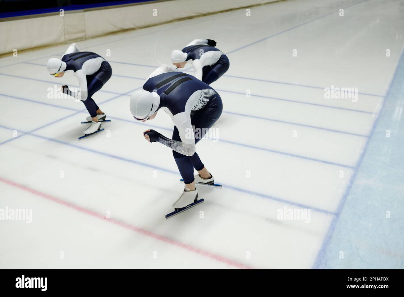 Three young sportsmen in sports uniform and skates bending forwards ...