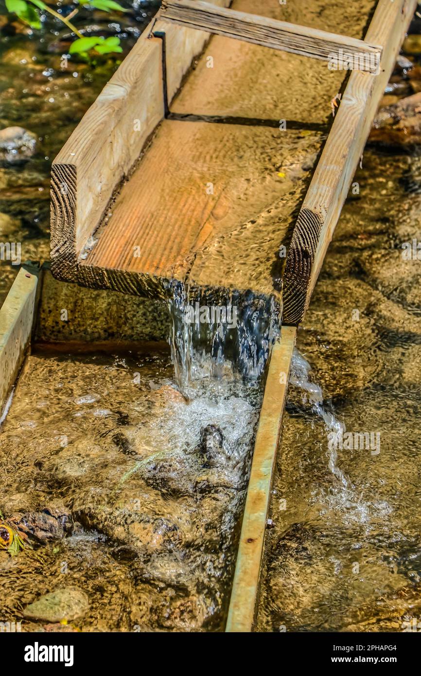 An empty wooden trough with a stream of water running down the sides ...