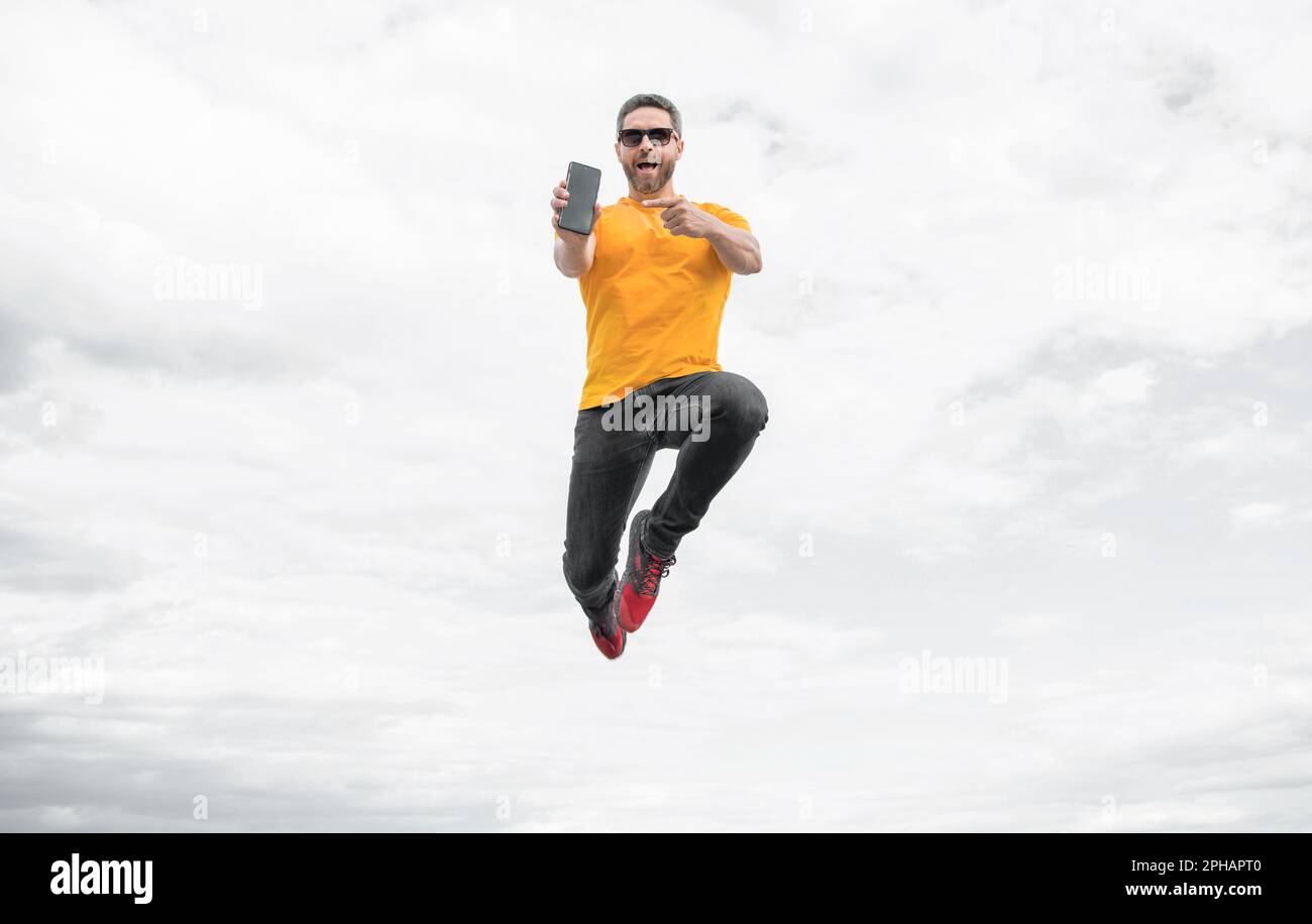 man jumping and presenting smartphone on sky background Stock Photo - Alamy