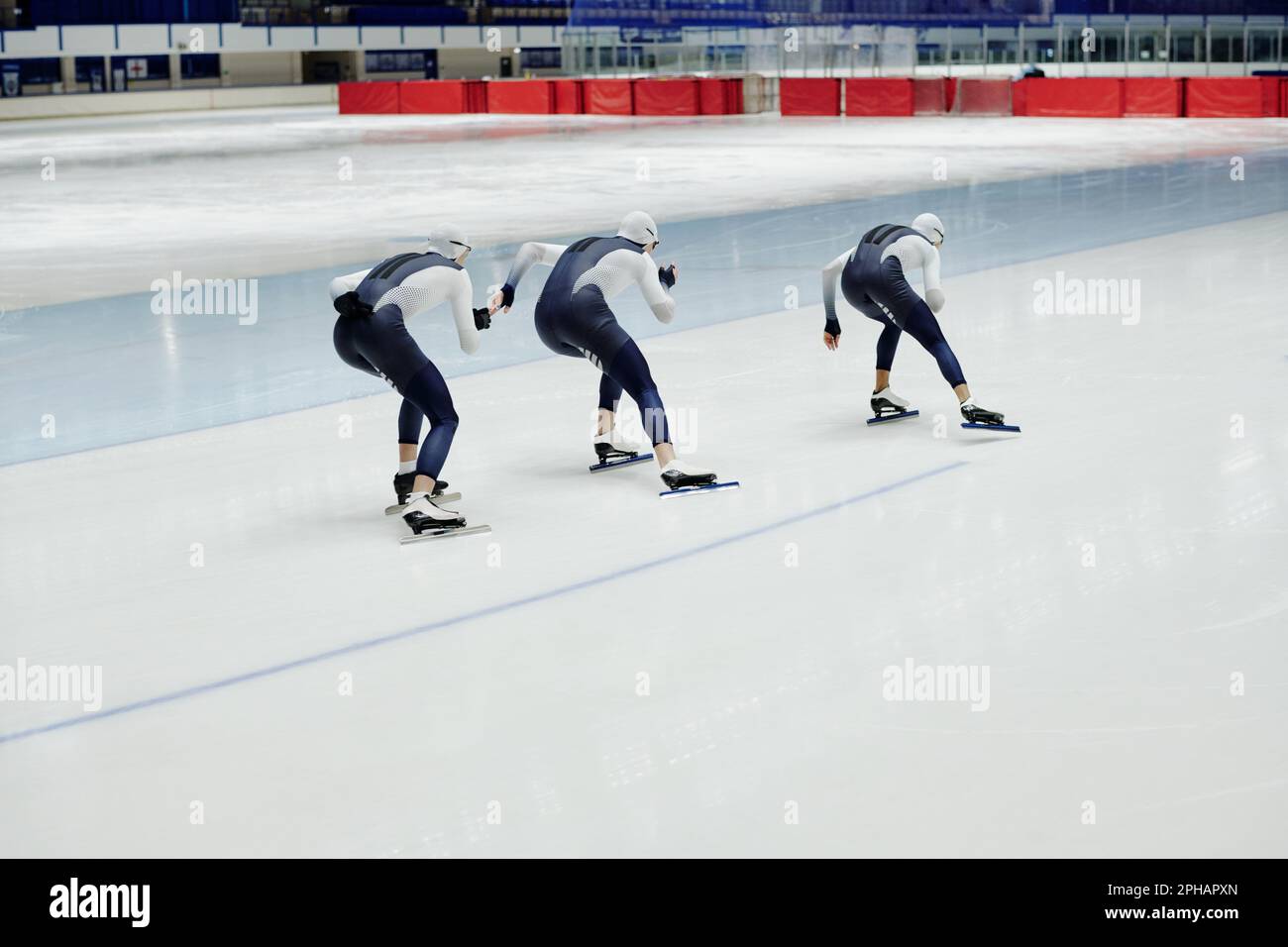 Row of three young sportsmen in sports uniform moving on ice along ...
