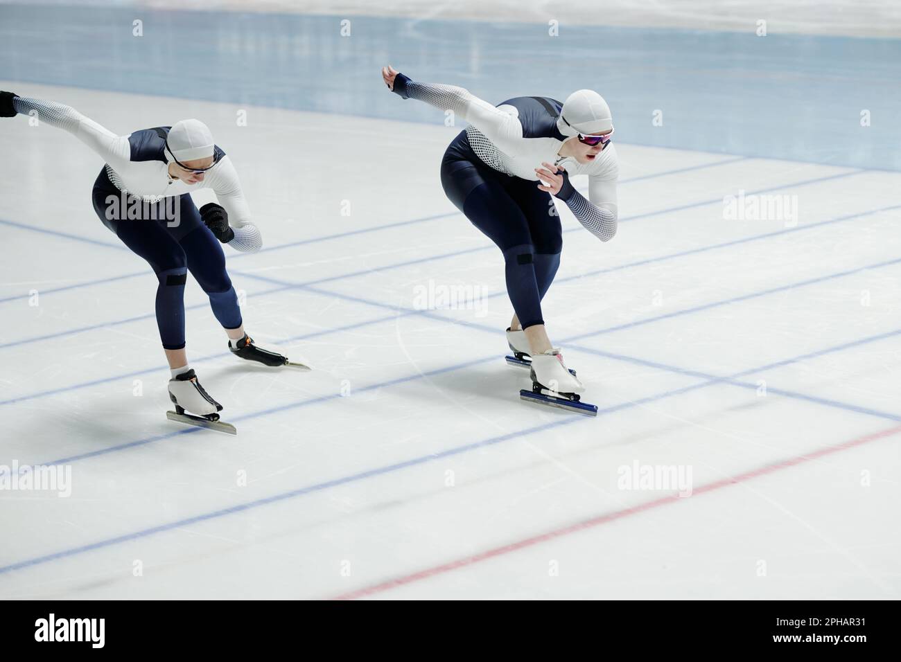 Two ypung male speed skaters in sports uniform moving forwards ...