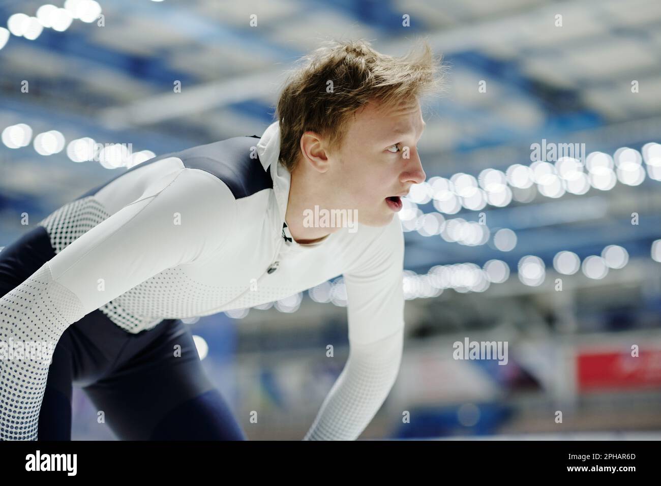 Youthful blond male athlete in sports uniform waiting for start signal ...