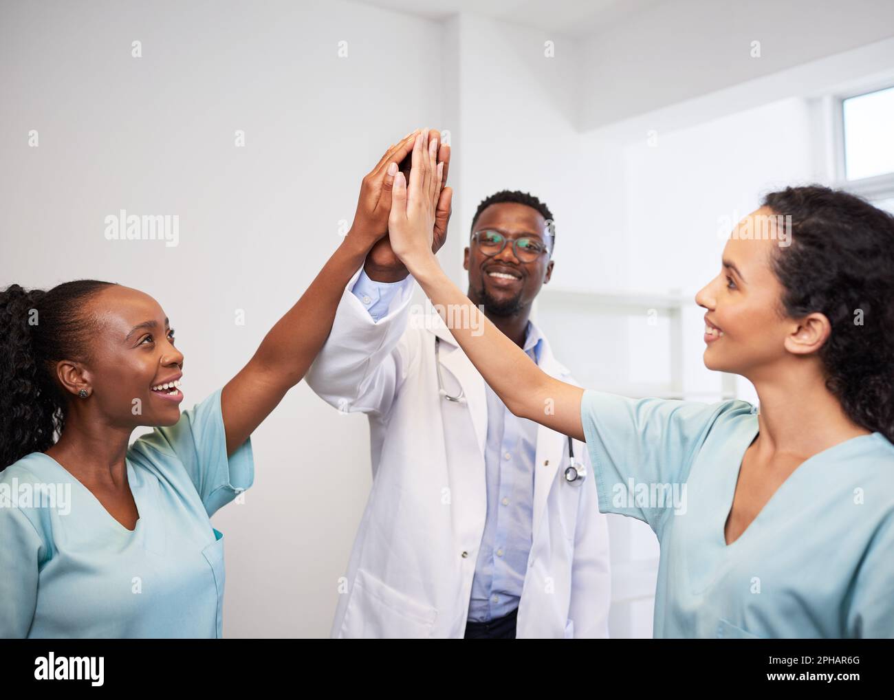 Three doctors share a high five, smile in hospital celebrate success ...