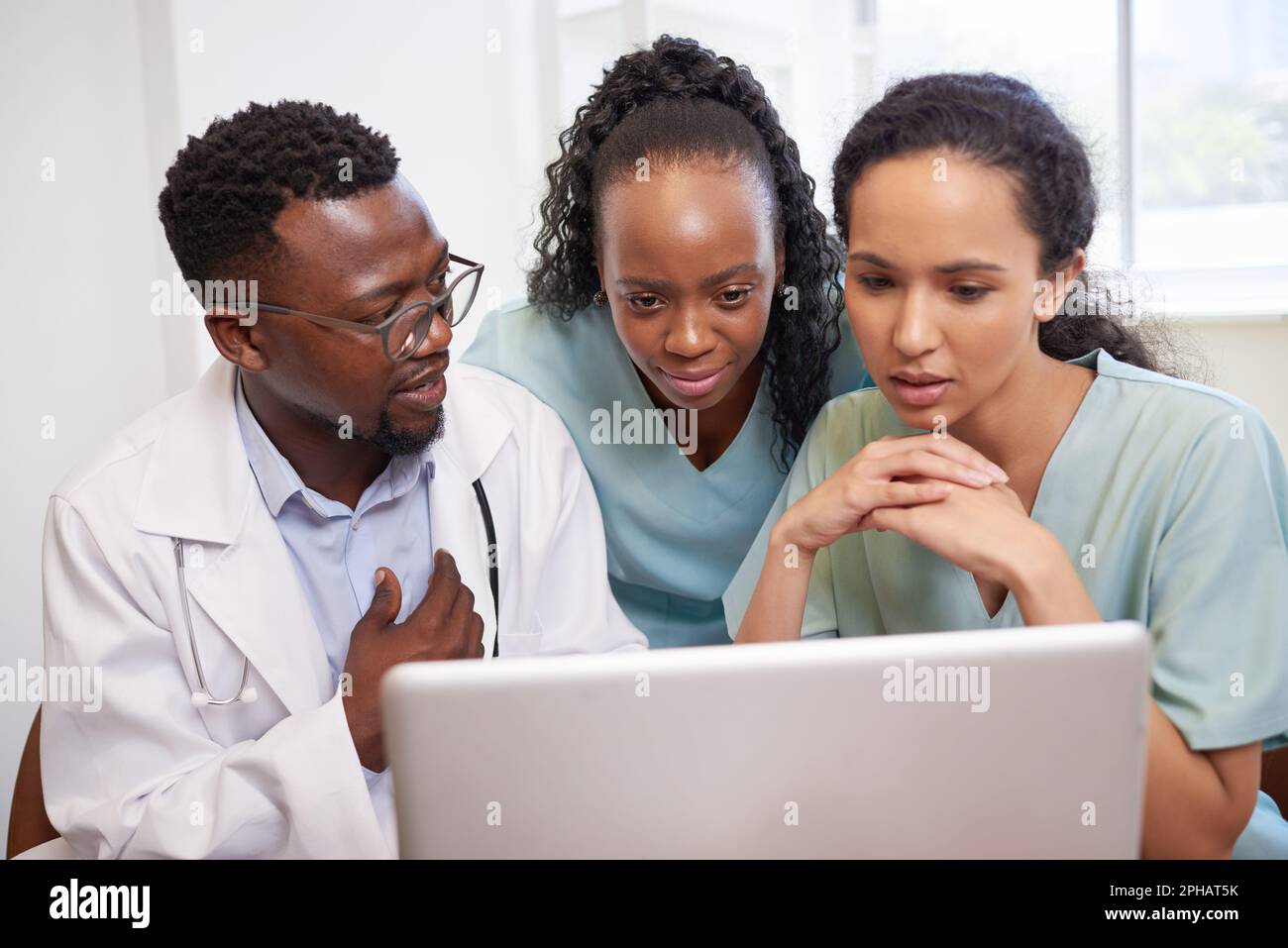 Three doctors look at laptop, serious review of patient case prep ...
