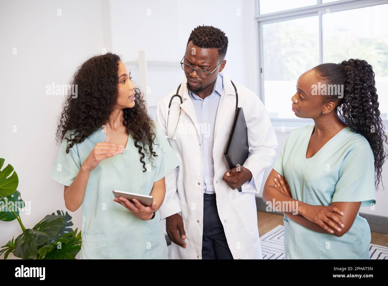 Medical team discuss patient case while standing looking serious ...