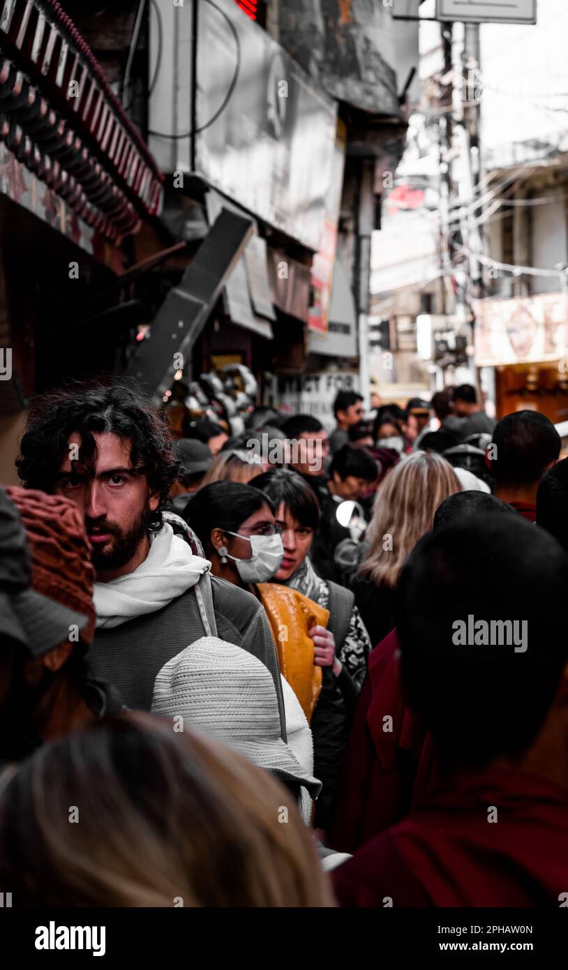 A bustling city street with a diverse crowd of people, walking past a ...