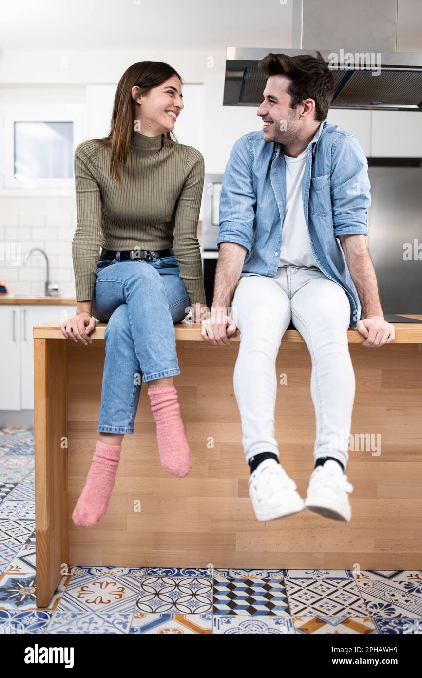 lovely young couple sitting on the kitchen table. Two cheerful young ...