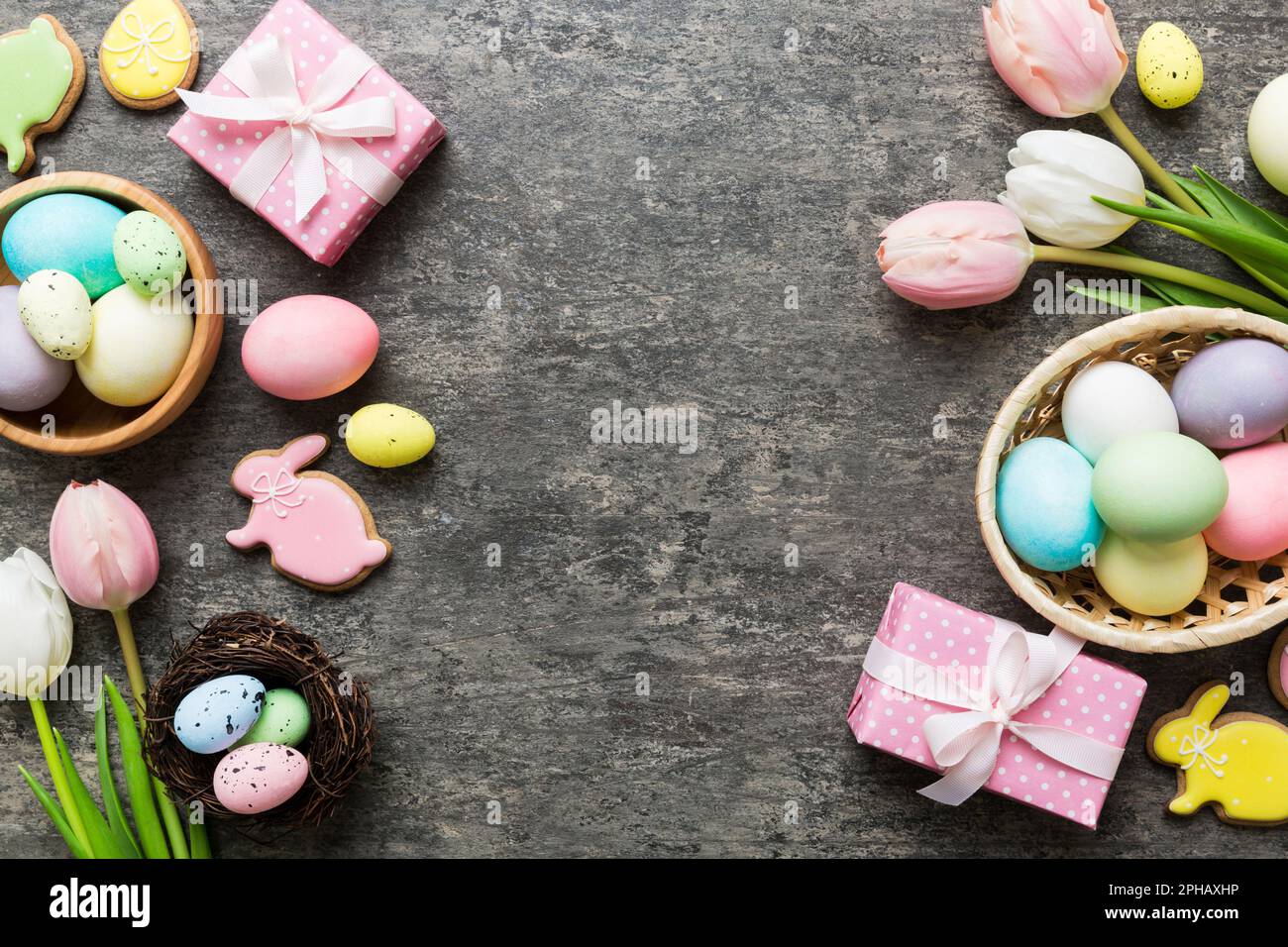 Easter frame with eggs, gift box and tulip on a colored background. The ...