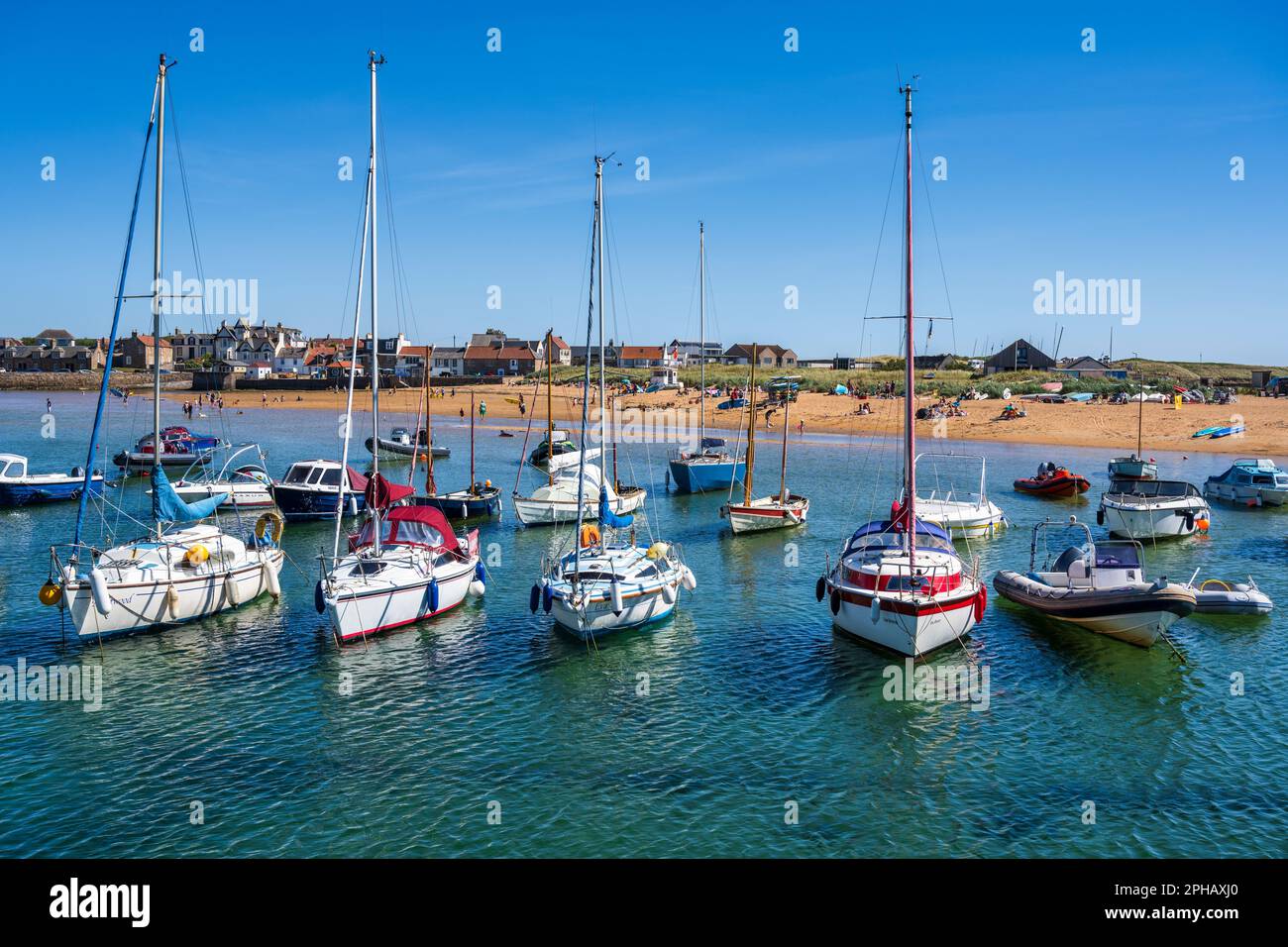 Boats moored in Elie harbour with Elie beach and town in background ...