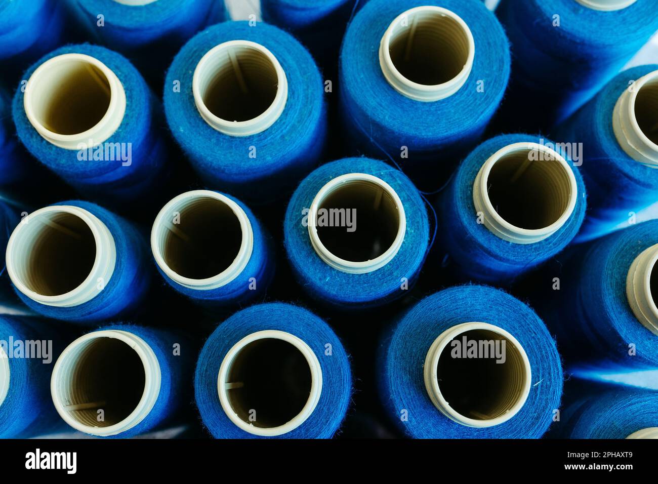 A high-resolution image of multiple blue spools of thread arranged in a ...