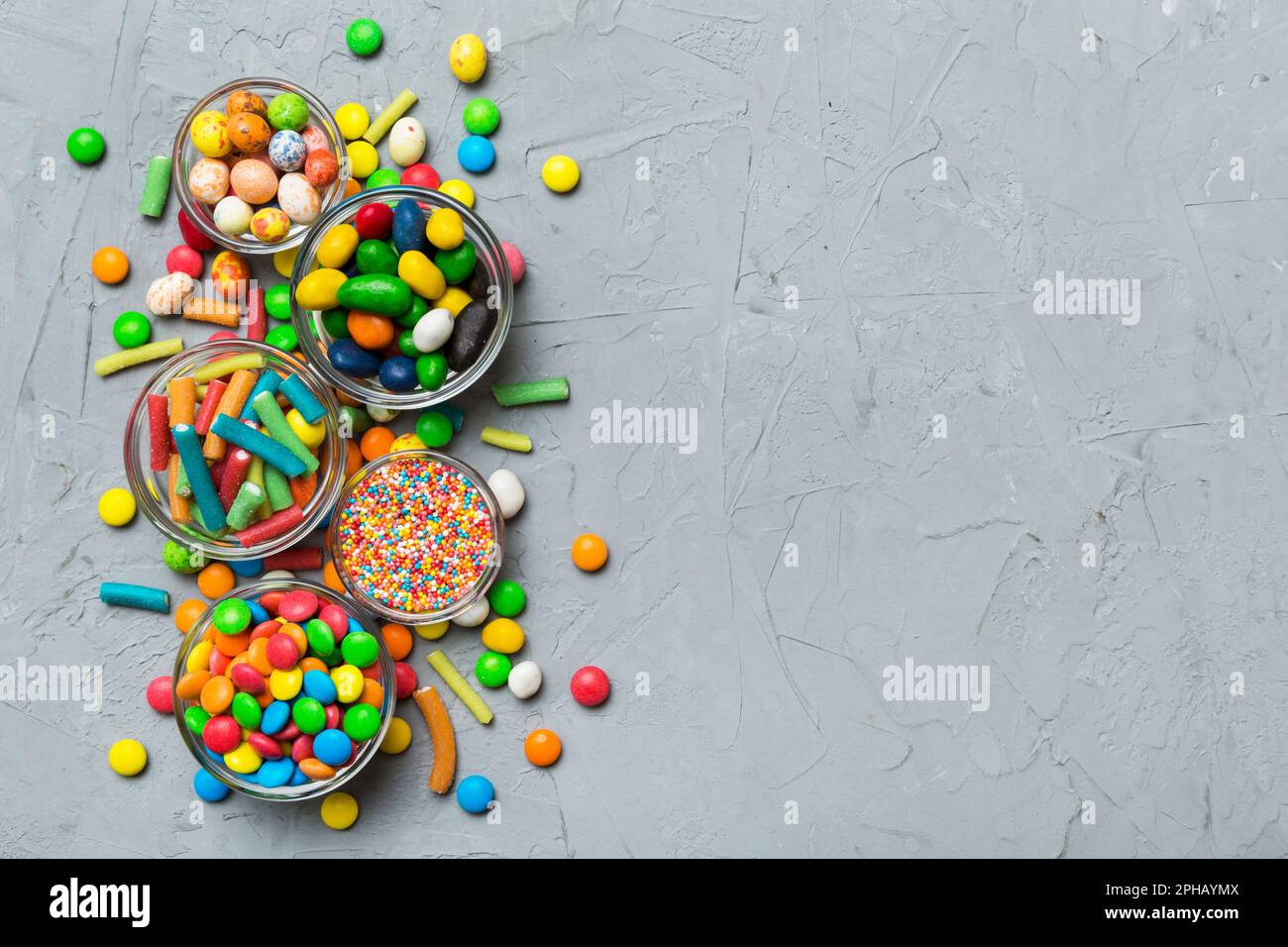 different colored round candy in bowl and jars. Top view of large ...