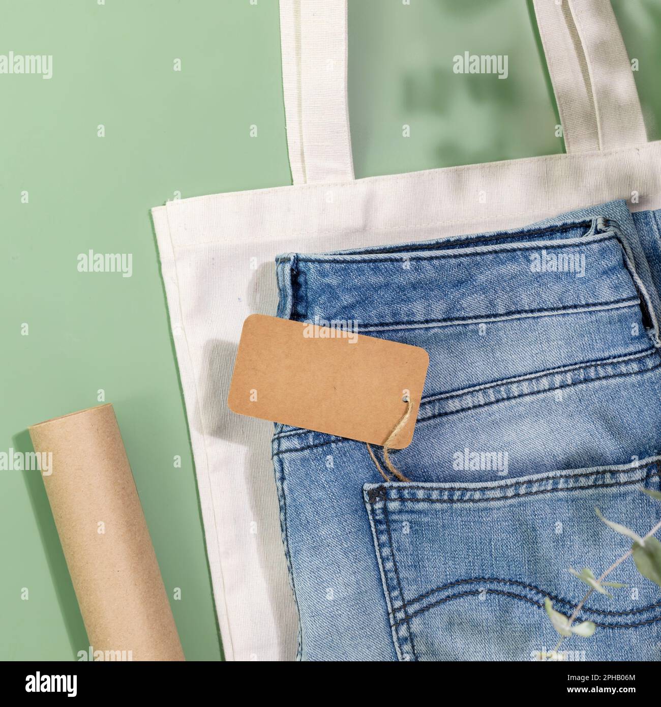 Sustainable flat lay with jeans with empty craft label, textile bag and ...