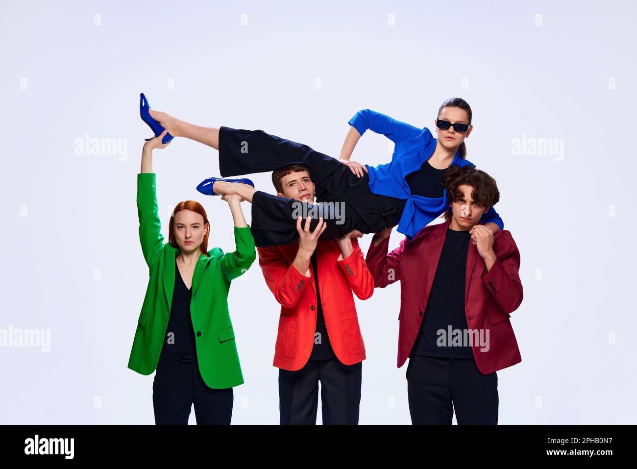 Group of young workers wearing jackets holding girl over head ...