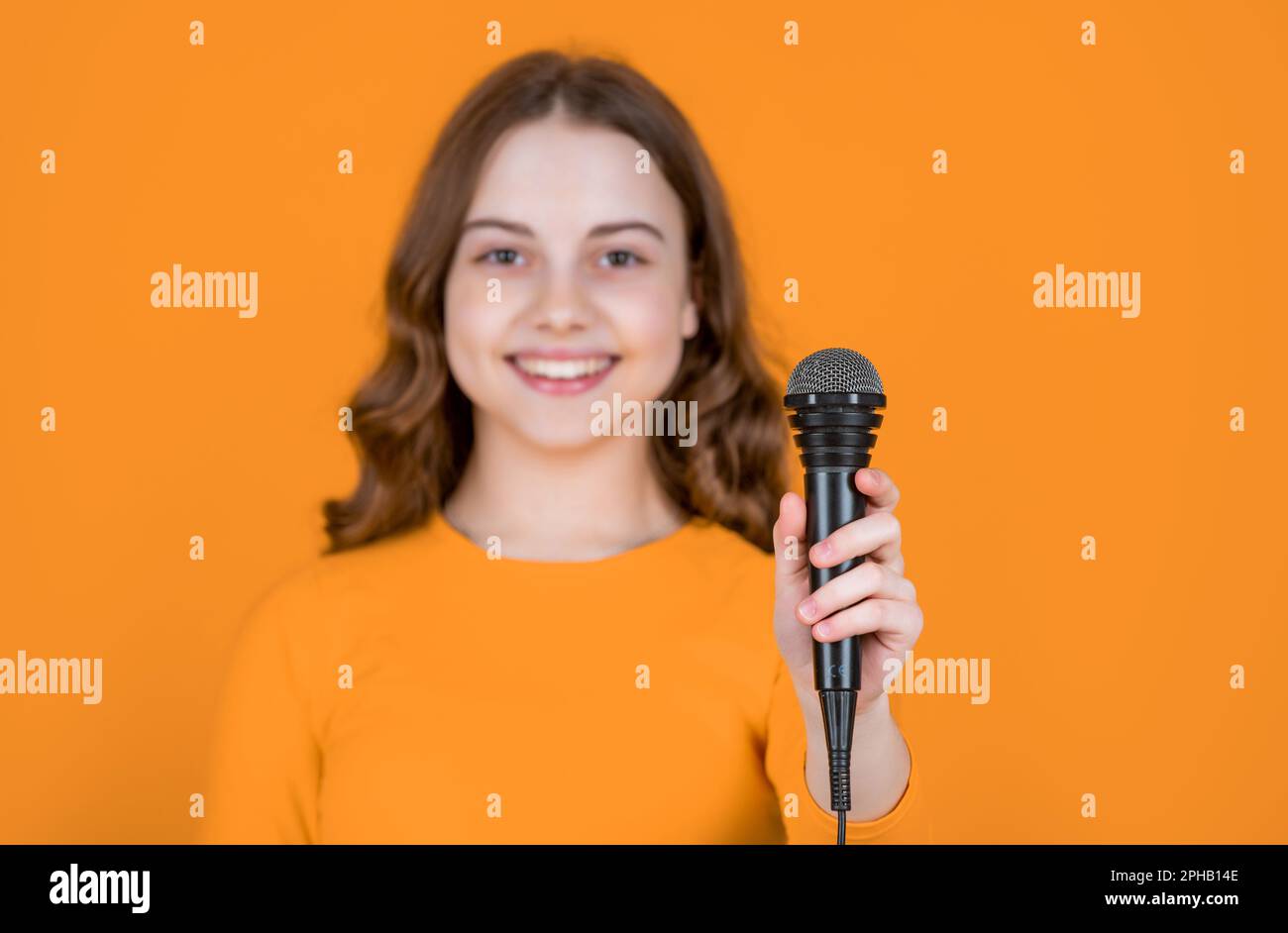 microphone in hand of teen girl on yellow background. selective focus ...