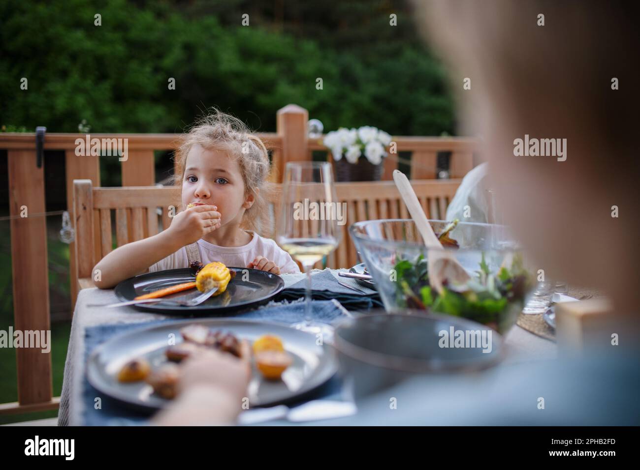 Family eating at barbecue party dinner on patio, little girl eating ...