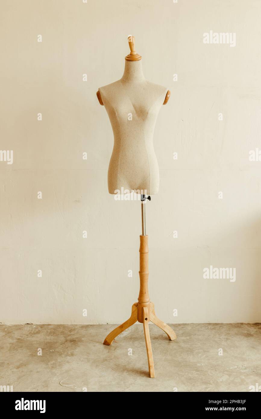 An isolated, white sewing mannequin is prominently displayed against a ...