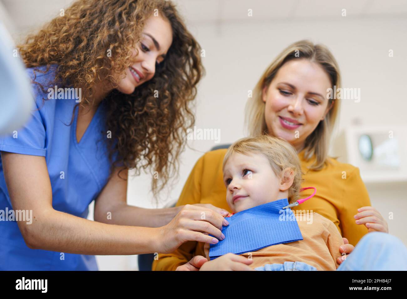 Little girl sitting with her mother on dentist chair, during preventive ...