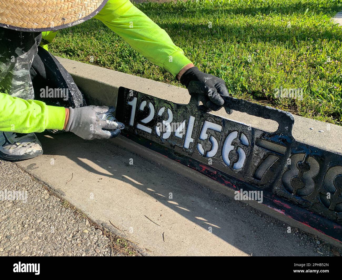 Public service worker in city repainting street addresses on the curb ...