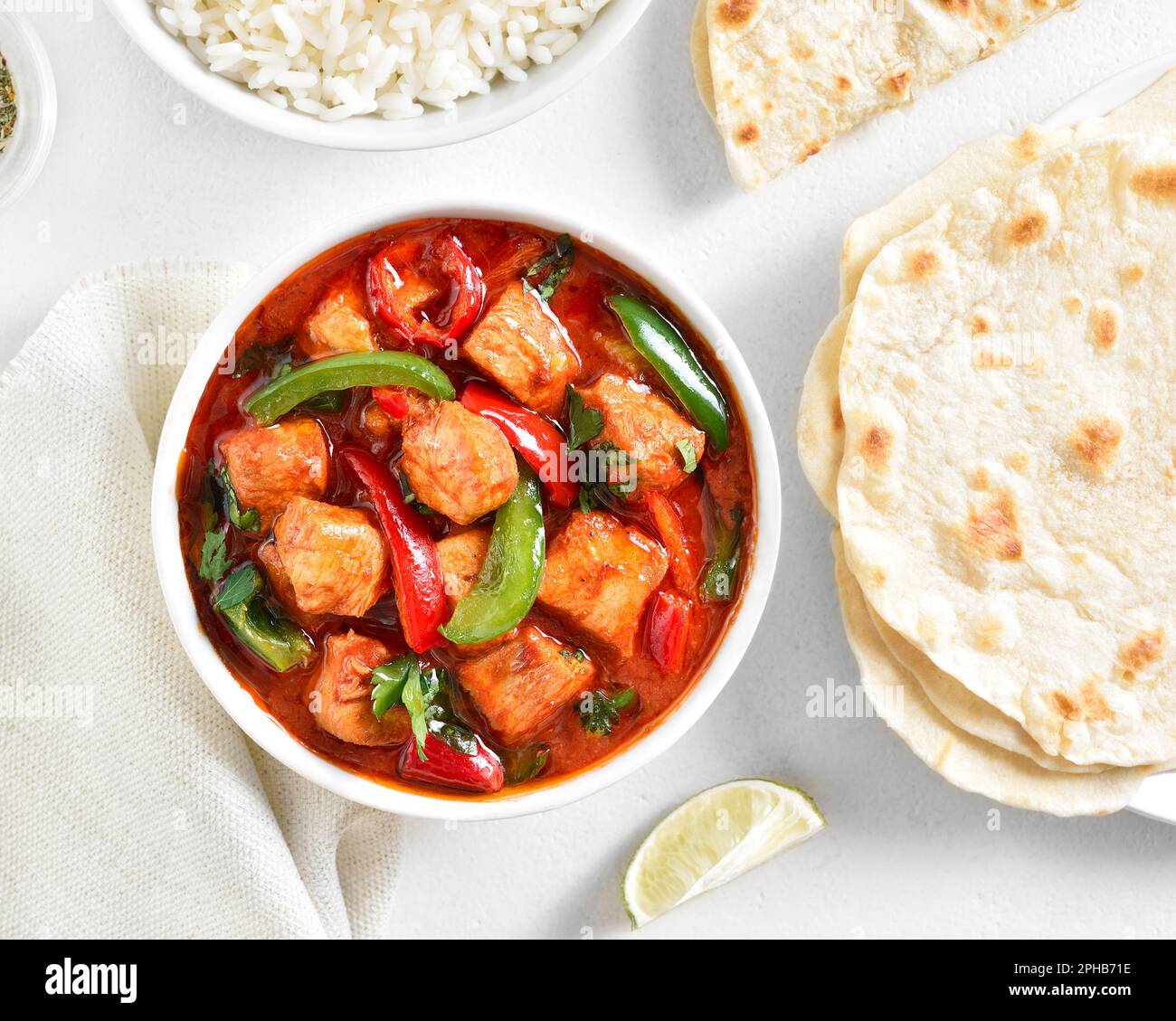 Thai style red chicken curry with vegetables in bowl over white stone ...