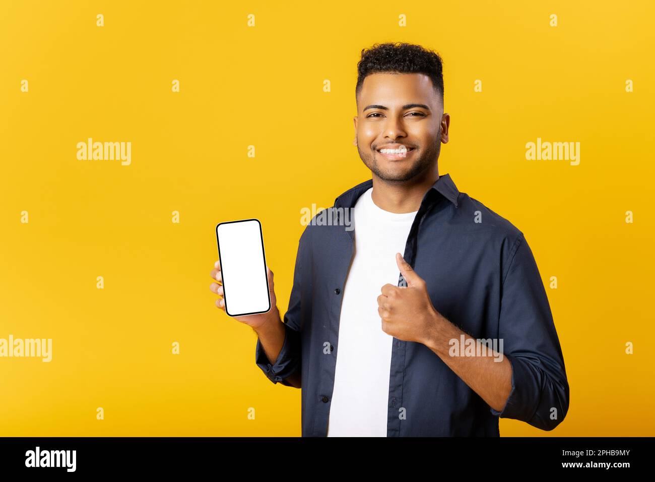 Happy young indian man looking at camera, holding smartphone with empty phone screen and showing ...